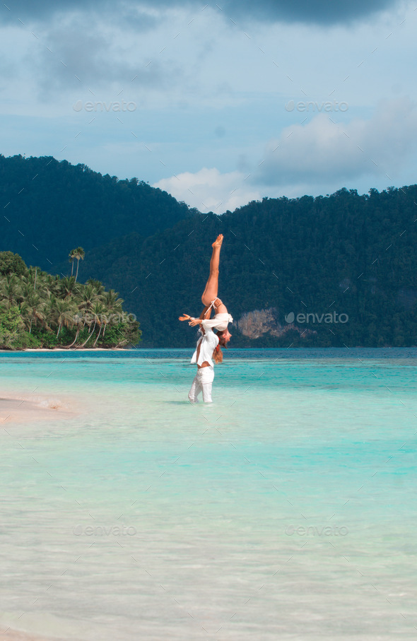 Couple do acrobatics on tropical beach Stock Photo by rikkicarman1