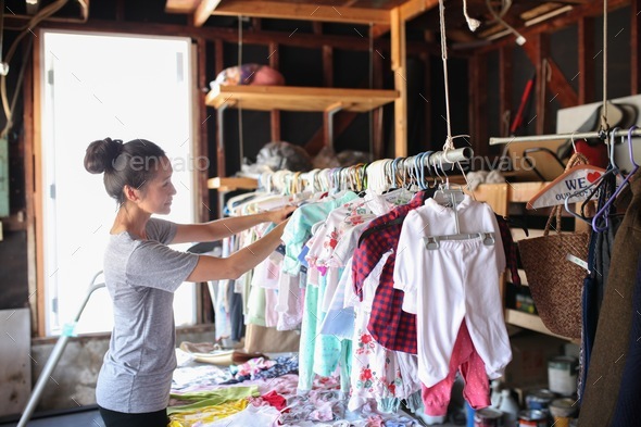 Female perusing racks of children’s clothing at a garage sale Stock ...