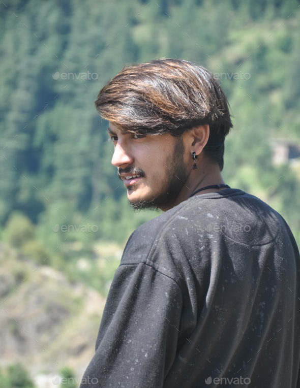 A handsome north Indian young guy standing outdoor with looking back ...