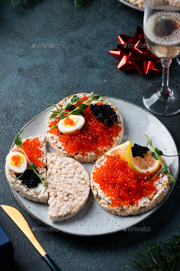 tartlets with red caviar, champagne and christmas decor. Rice cake with ...