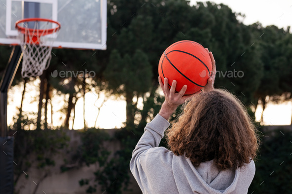 man throwing a ball into a basketball hoop Stock Photo by Raul_Mellado