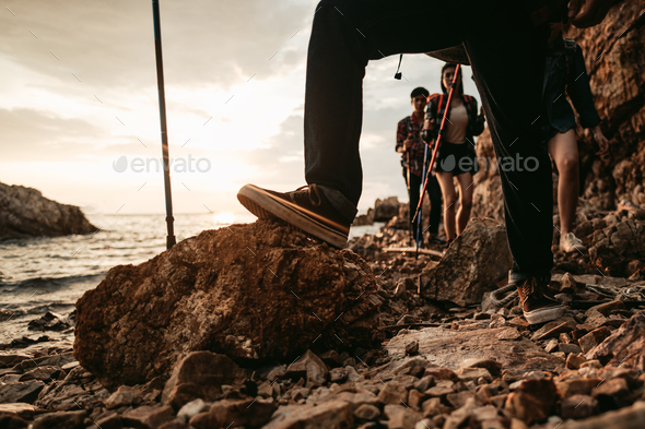Hikers walking on the rocks in the middle of the sea.Teamwork and ...