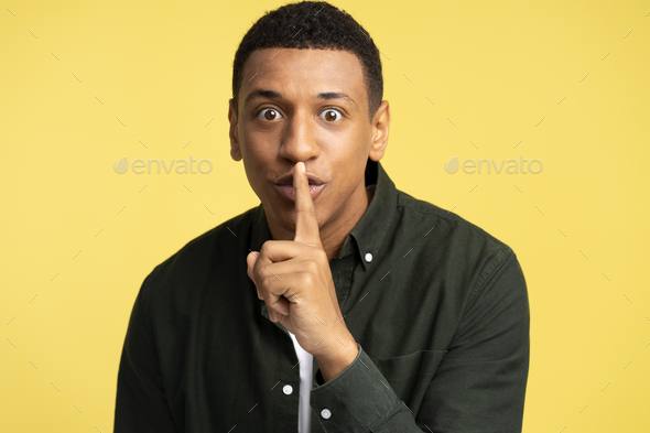 Portrait of optimistic positive man standing, showing hush sign ...