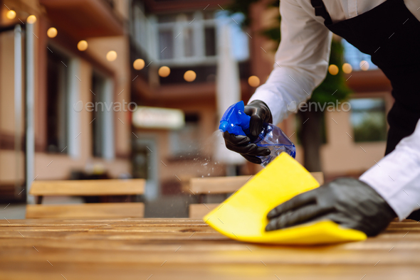 Disinfecting to prevent COVID-19. Waiter cleaning the table with ...