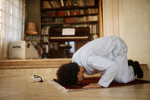 Religious Middle Eastern man praying at home. Stock Photo by drazenphoto