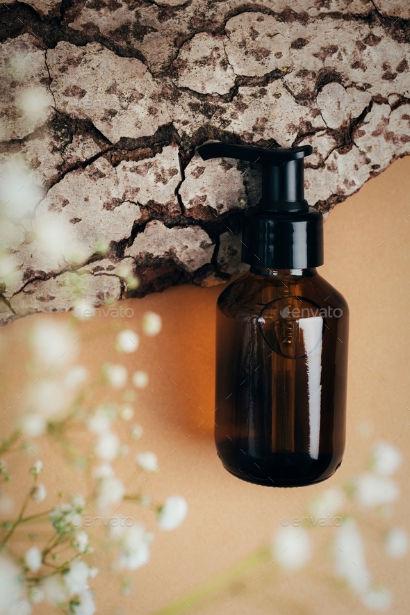 Bottle of cosmetic face cleanser on tree bark. Spa and wellness concept ...