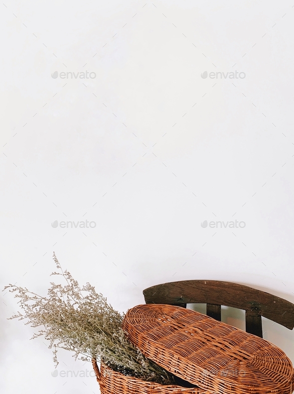 Bunch of dry flowers in wicker basket on wooden chair in modern clean ...