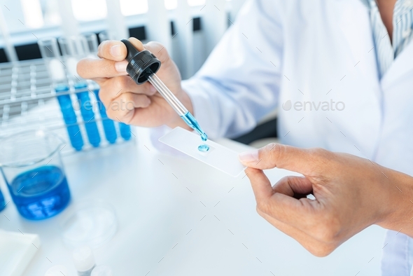 Scientist woman holding dropper to dropping solution sample on the ...