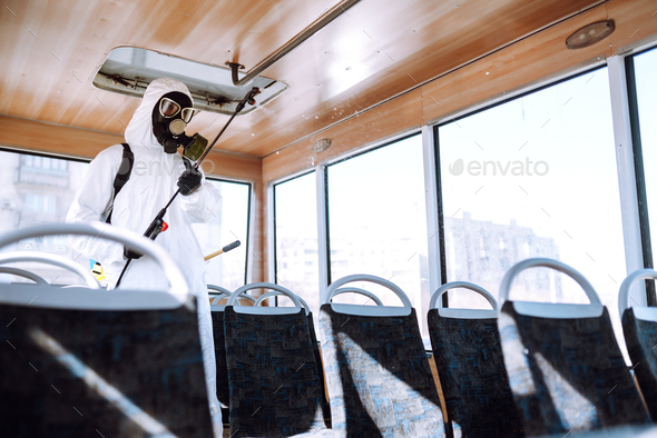 Cleaning and Disinfection transport. Man in protective suit washing ...