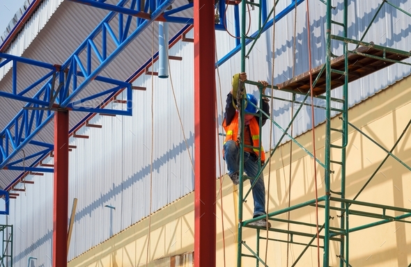 Construction worker climbing on scaffolding to working on roof ...