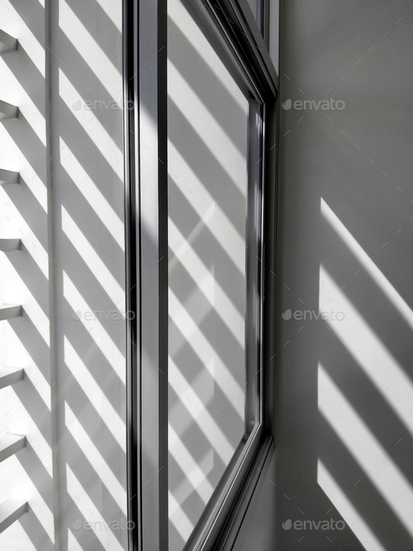 Sunlight and shadow of sunshade battens on surface of glass window in ...