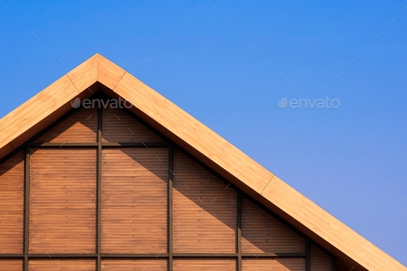 Vntage wooden gable roof with battens decoration against blue clear sky ...