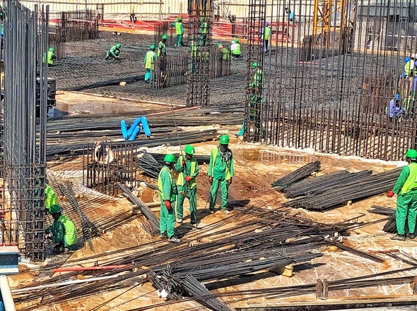 Construction Men working together in desert heat constructing high rise ...