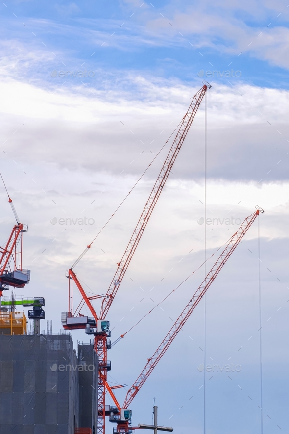 Group of tower cranes working on top of high building structure against ...