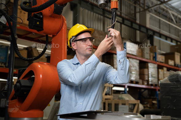 Engineer working in factory looking automatic robotic arm welding head ...