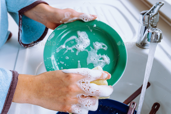 Woman's hands washing plate in kitchen sink Stock Photo by larisikstefania