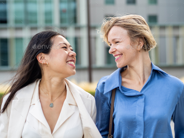 Two business women walking and talking to each other in a financial ...