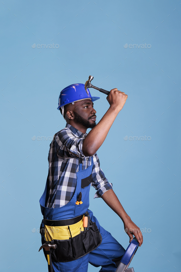 Construction worker on ladder using hammer Stock Photo by DC_Studio