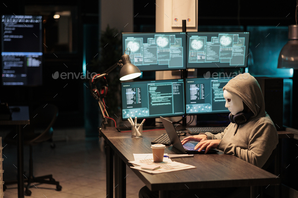 Scammer with mask and hood hacking security server Stock Photo by DC_Studio
