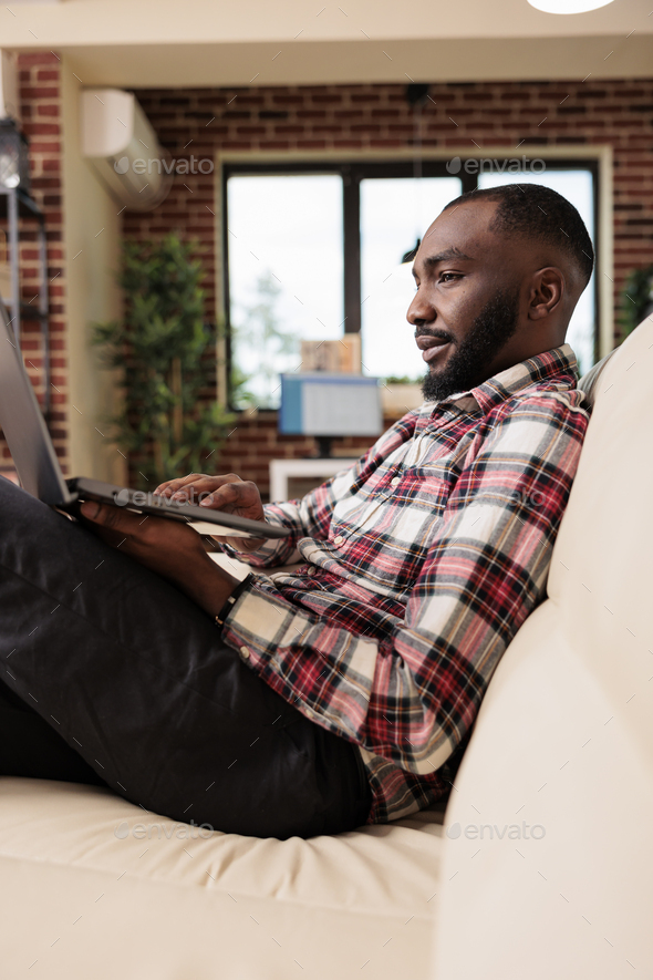 Male freelancer working on laptop at home Stock Photo by DC_Studio
