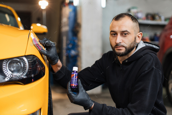 Skillful and professional male auto service worker polishing and ...