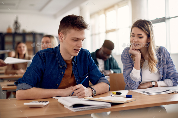 Smiling university classmates studying during class in the classroom ...