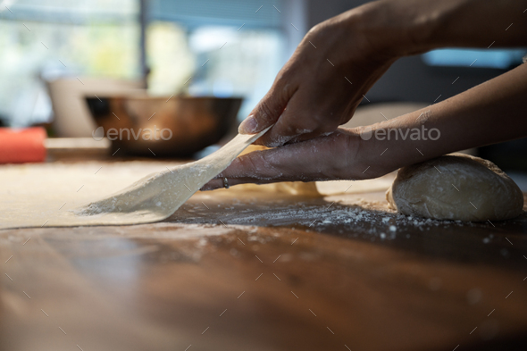 Low angle view of a woman stretching and pulling homemade vegan pastry ...