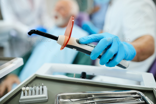 Close-up of dentist using dental curing light during dental procedure ...