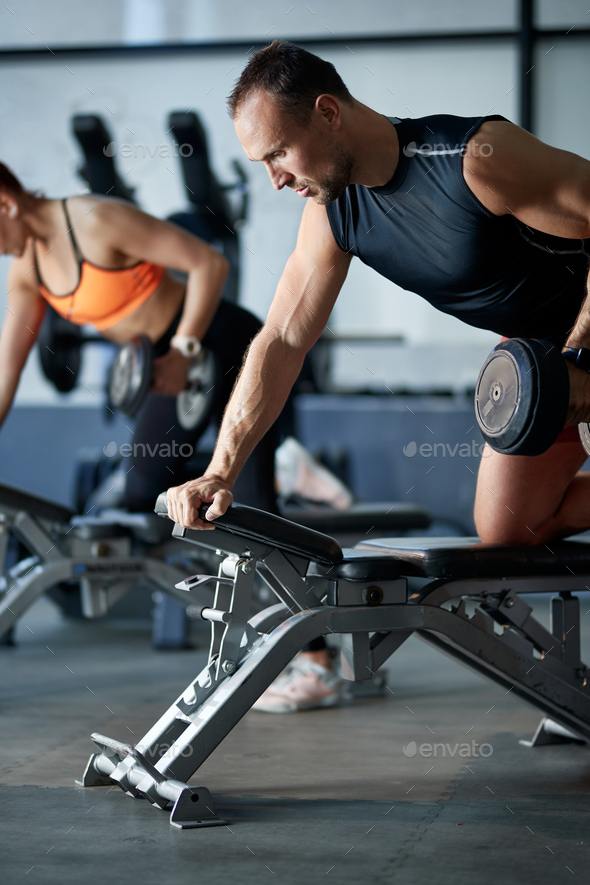 Muscular build man working out with hand weight during sports training ...
