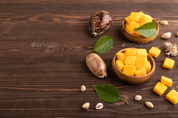 Dried mango cubes in wooden bowls on brown wooden, side view, copy ...