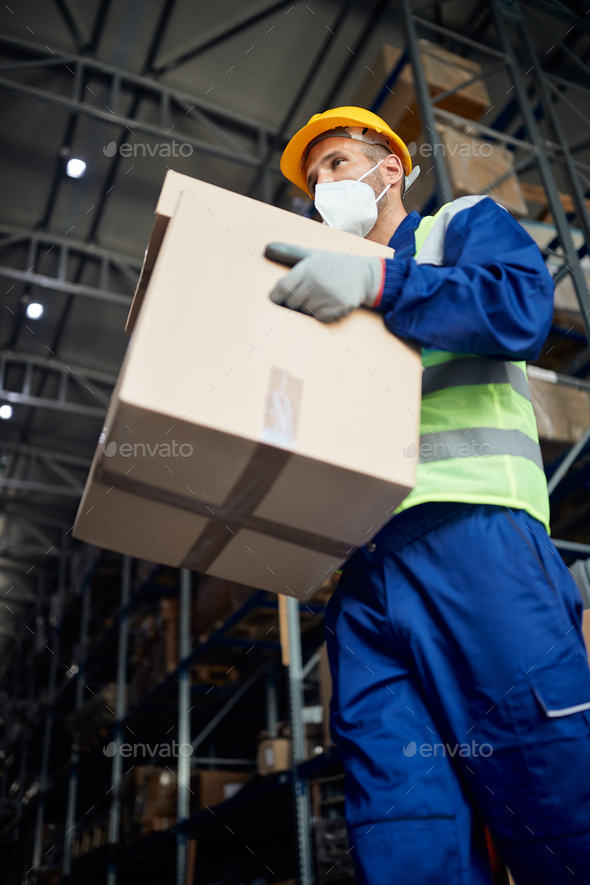 Low angle view of warehouse worker working at storage compartment ...