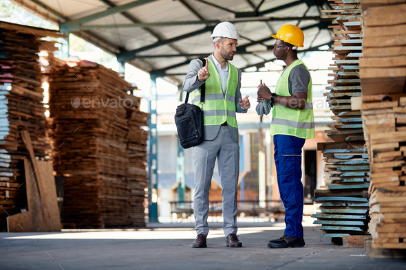 Warehouse inspector gives instructions to African American worker in ...