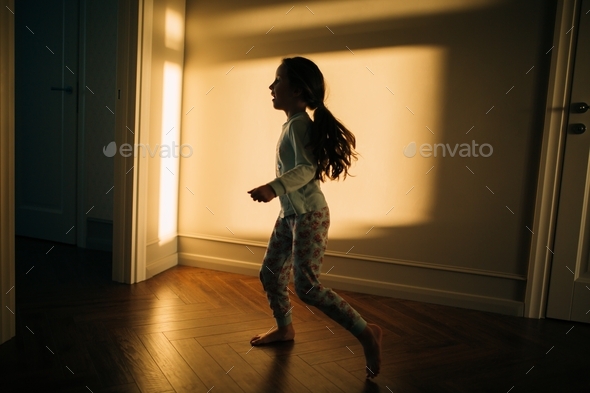 Situette of a happy little girl running around the apartment before ...