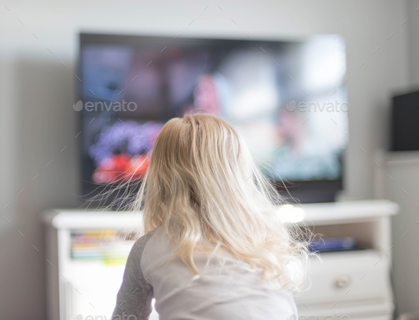 Back view of girl watching TV in morning sunlight Stock Photo by krisprahl