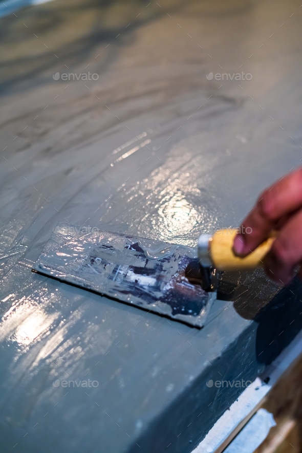 closeup worker applying micro concrete plaster coating on the kitchen ...
