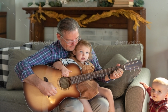 Grandpa playing guitar with his young granddaughter Stock Photo by ...