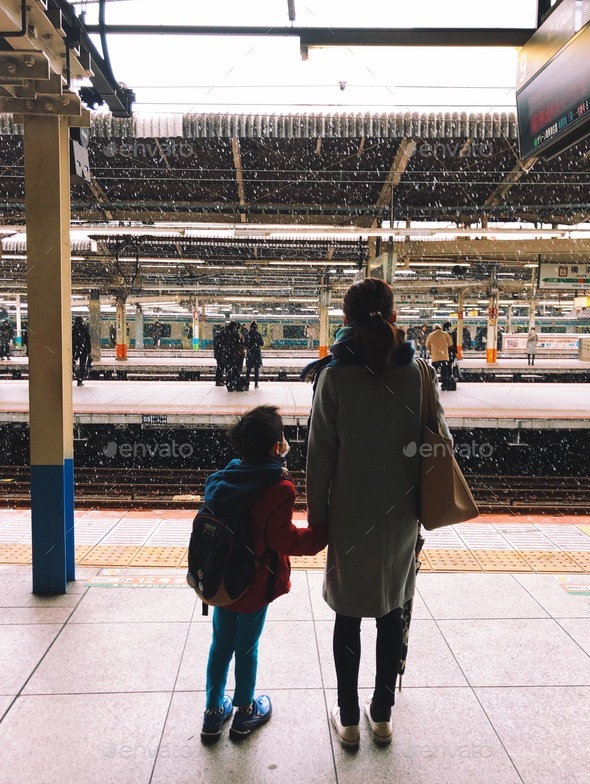 Son and mother waiting for a train at a snowy station. Stock Photo by jonathancant