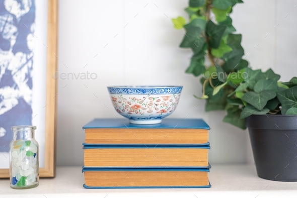 Stack of books with vintage pottery on a shelf Stock Photo by krisprahl