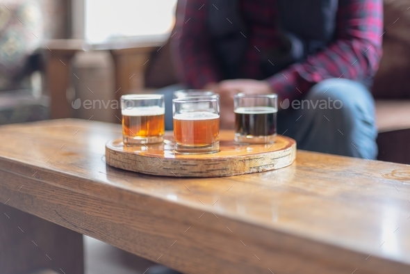 Man sitting on a couch in a brewery with a beer flight on the table in ...