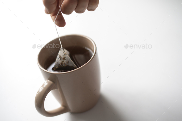 a person's hand holding a tea bag and making hot cup of tea Stock Photo ...