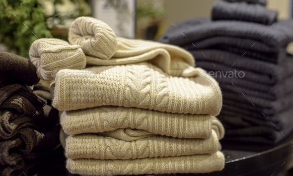 Stack of neatly folded cable knit sweaters on display at a retail store ...