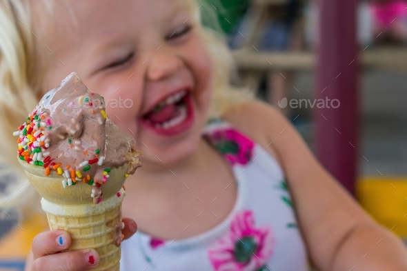 Laughing child holding melting ice cream cone Stock Photo by krisprahl