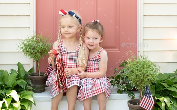 Two little girls sitting on the back steps on Fourth of July Stock ...