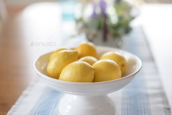 Bowl of lemons on dining table in natural light Stock Photo by krisprahl