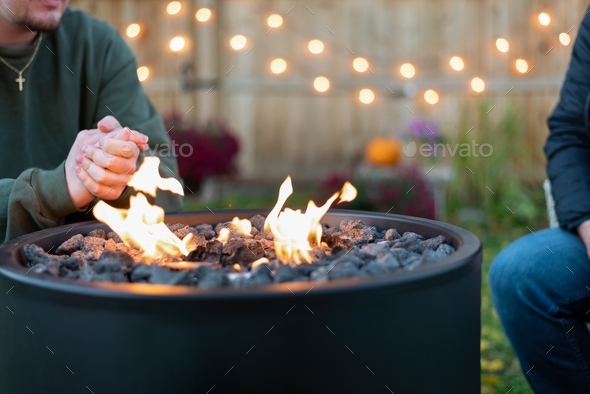People sitting around a backyard fire pit Stock Photo by krisprahl
