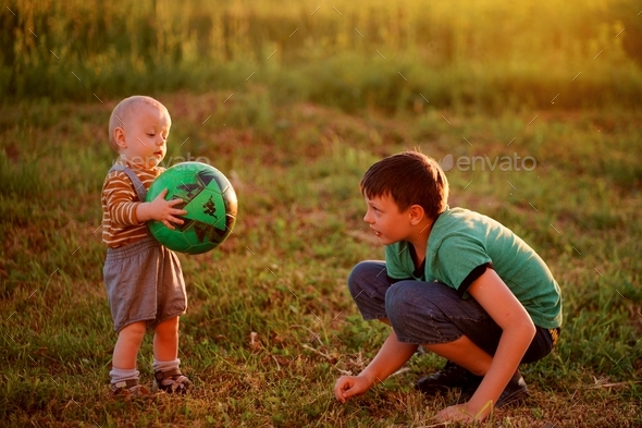 boy playing football with his younger brother Stock Photo by Repnitskaya