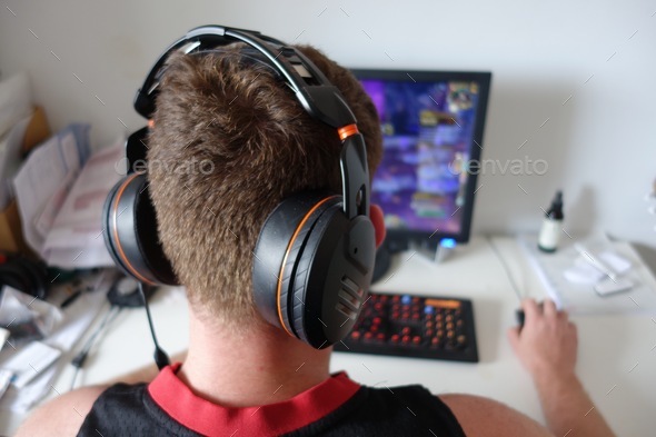 Young man playing video games on computer with headphones Stock Photo ...