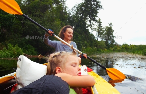 Girl sleeping in a kayak, mom working with a paddle, family weekend ...