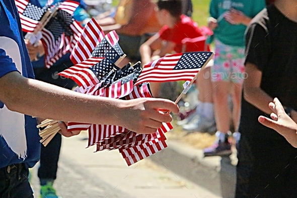People passing out American flags along the street at a local ...