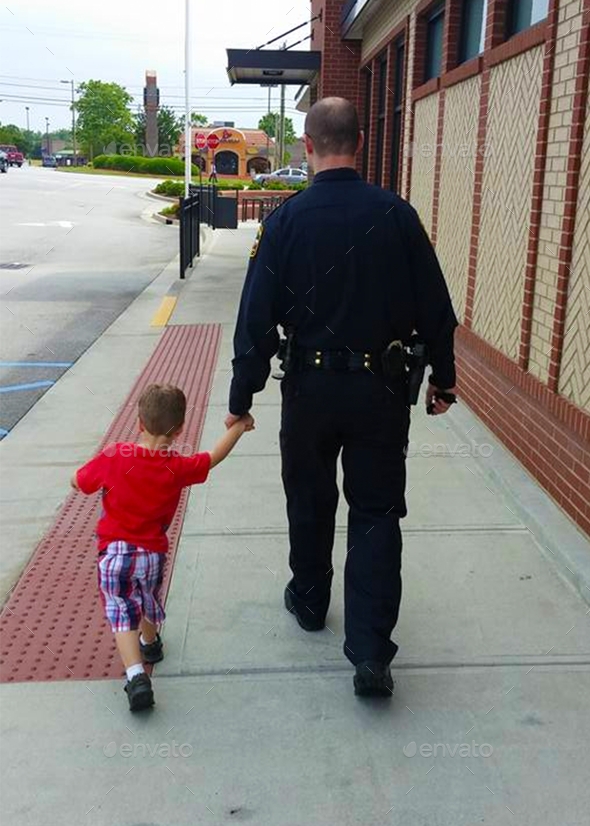 Law enforcement officer holding hands with his little boy. Stock Photo ...